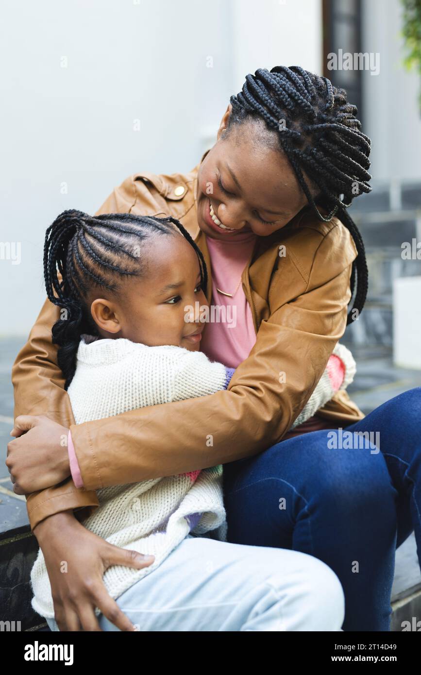 Happy african american mother and daughter embracing on steps in front of house Stock Photo - Alamy