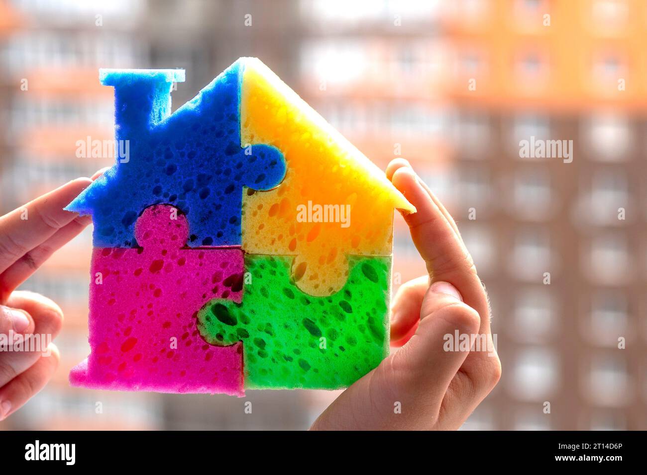 Hands holding a house against the background of a multi-storey building ...