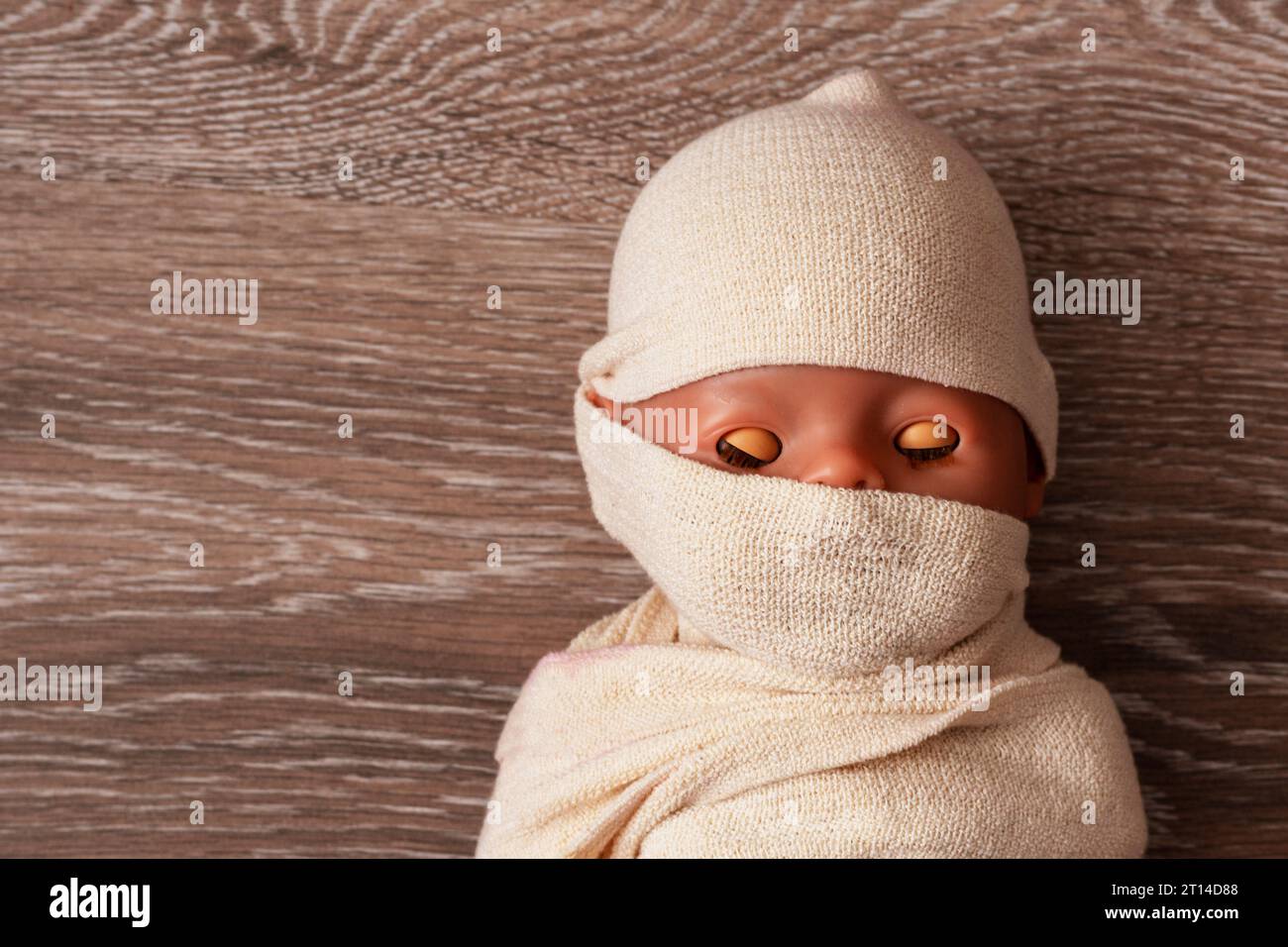 The doll the baby is wound with fabric. The body of the child is ...