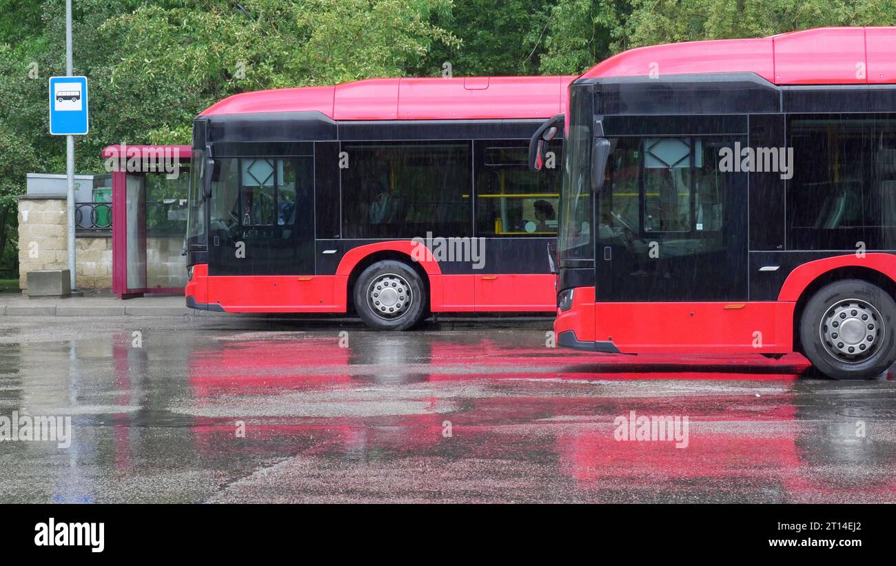 Two red buses waiting at the bus station during rain Stock Photo - Alamy