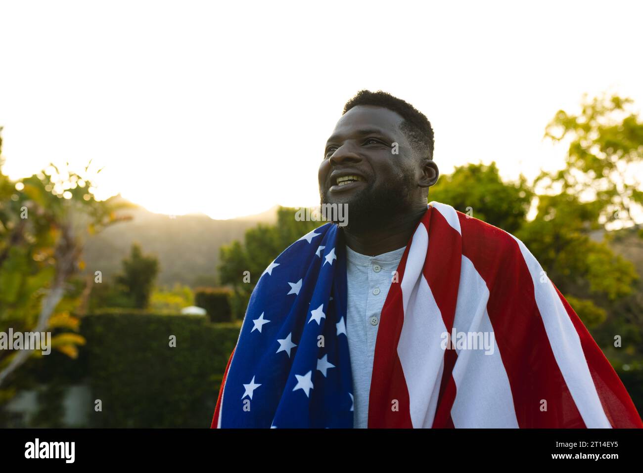 Happy african american man with flag on back american flag in sunny ...