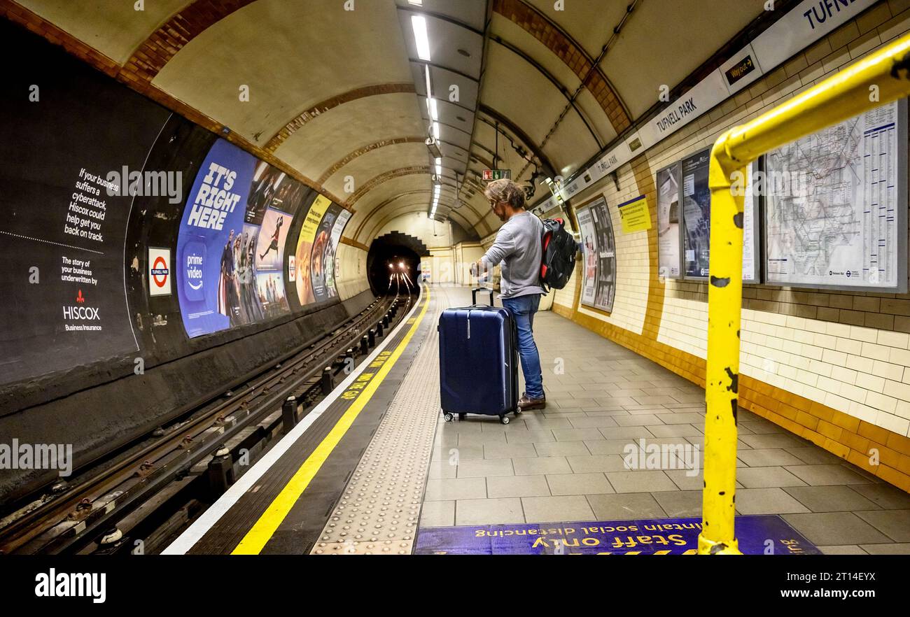 London, UK. Man with luggage waiting for a tube train at Tufnell Park ...