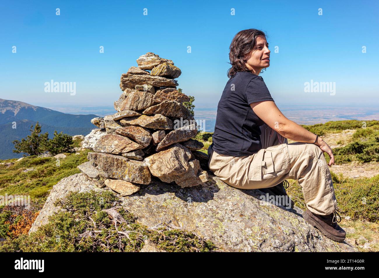 Woman sitting next to a milestone, resting after ascending to the top ...