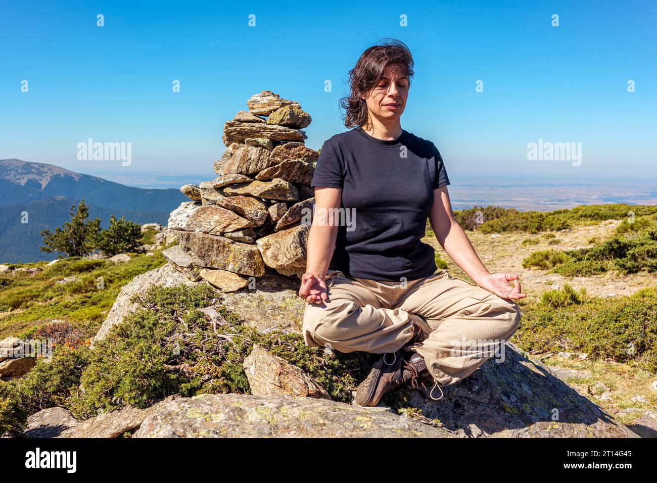 Woman sitting next to a milestone in easy position, with her hands in a ...