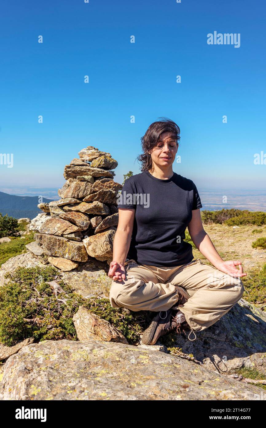 Woman sitting next to a milestone in easy position, with her hands in a ...