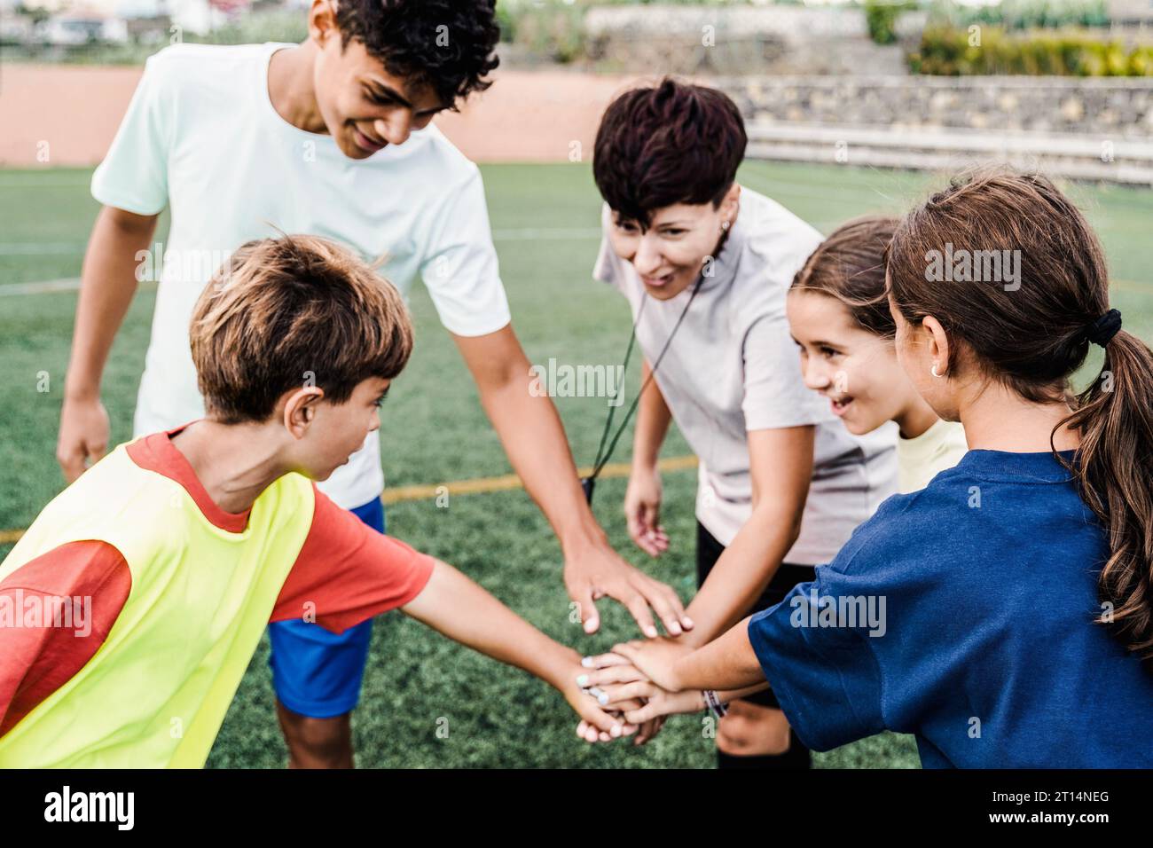 Happy group of kid soccer players stacking hands having fun together ...
