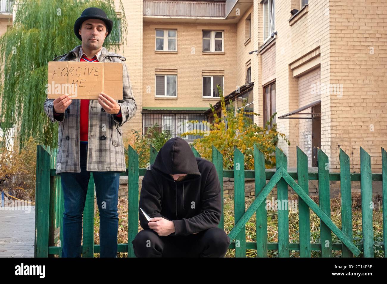 Forgiveness concept. Two men with a knife and a sign forgive me on a ...