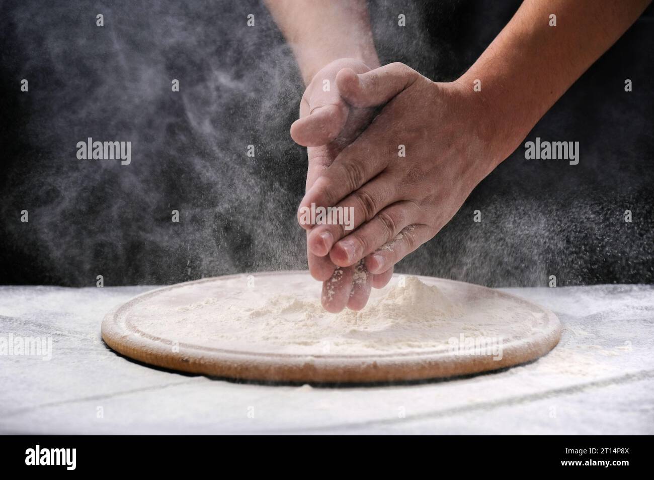 A man claps his hands with a splash of white flour and a black ...