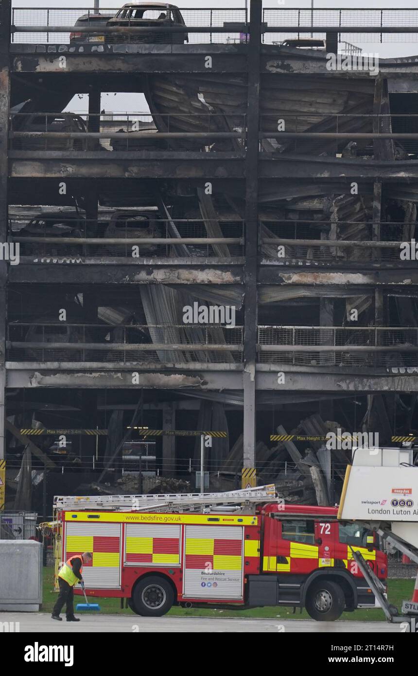The burnt out shells of cars, buried amongst debris of a multi-storey car park at Luton Airport ...