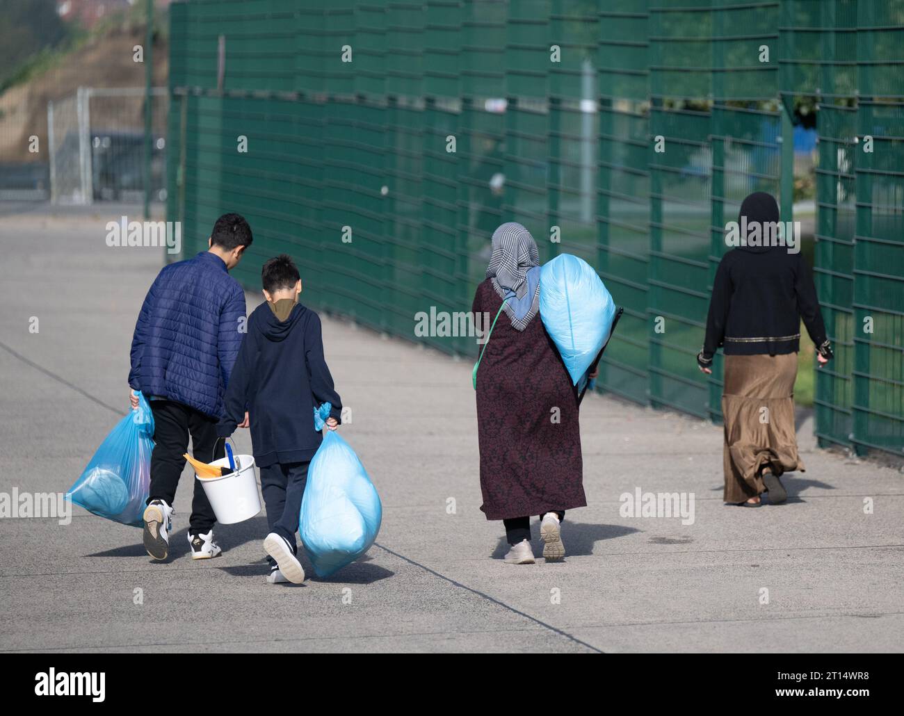 11 October 2023, Hesse, Gießen: Newly arrived refugees carry their ...
