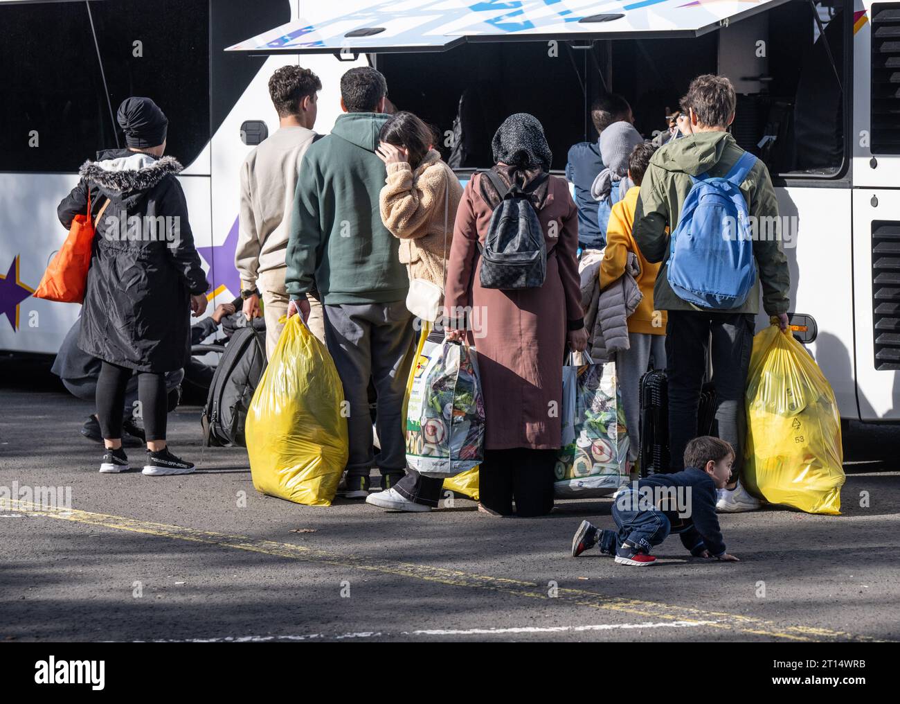 11 October 2023, Hesse, Gießen: Refugees walk to a waiting bus at the ...