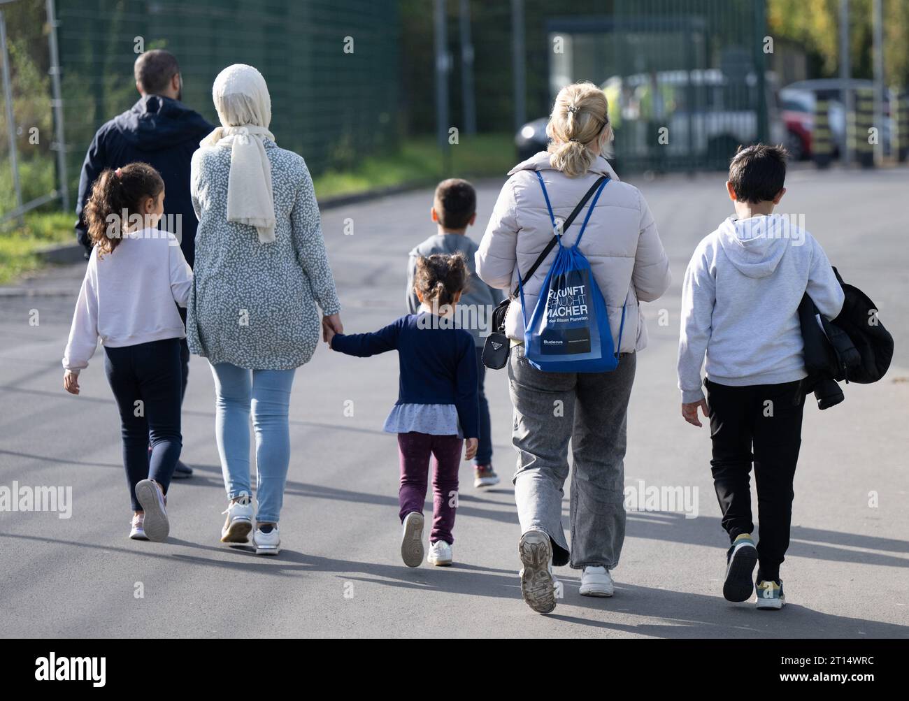 11 October 2023, Hesse, Gießen: A family walks to their accommodation ...