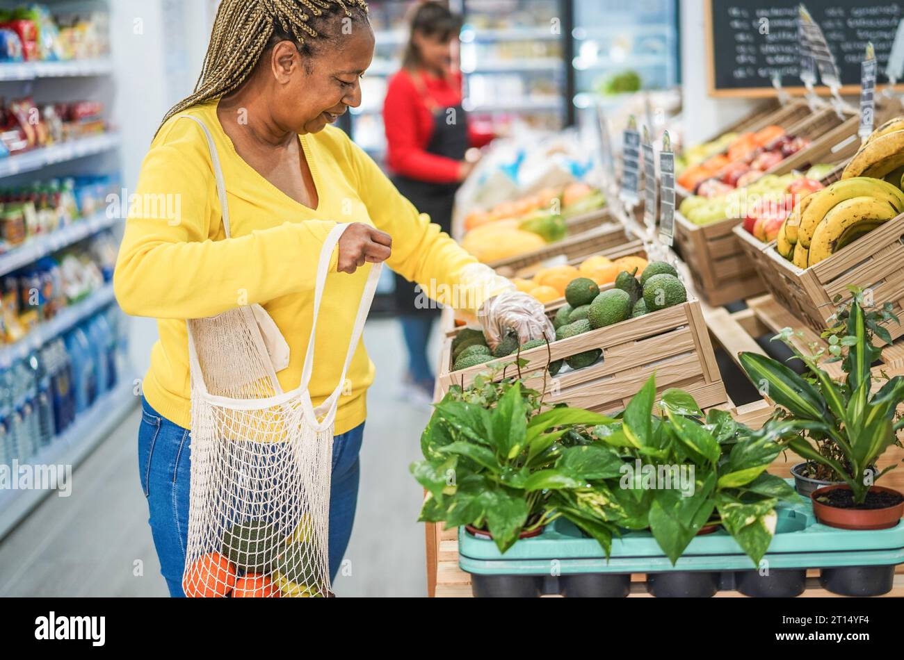 African female customer buying organic food fruits inside minimarket ...