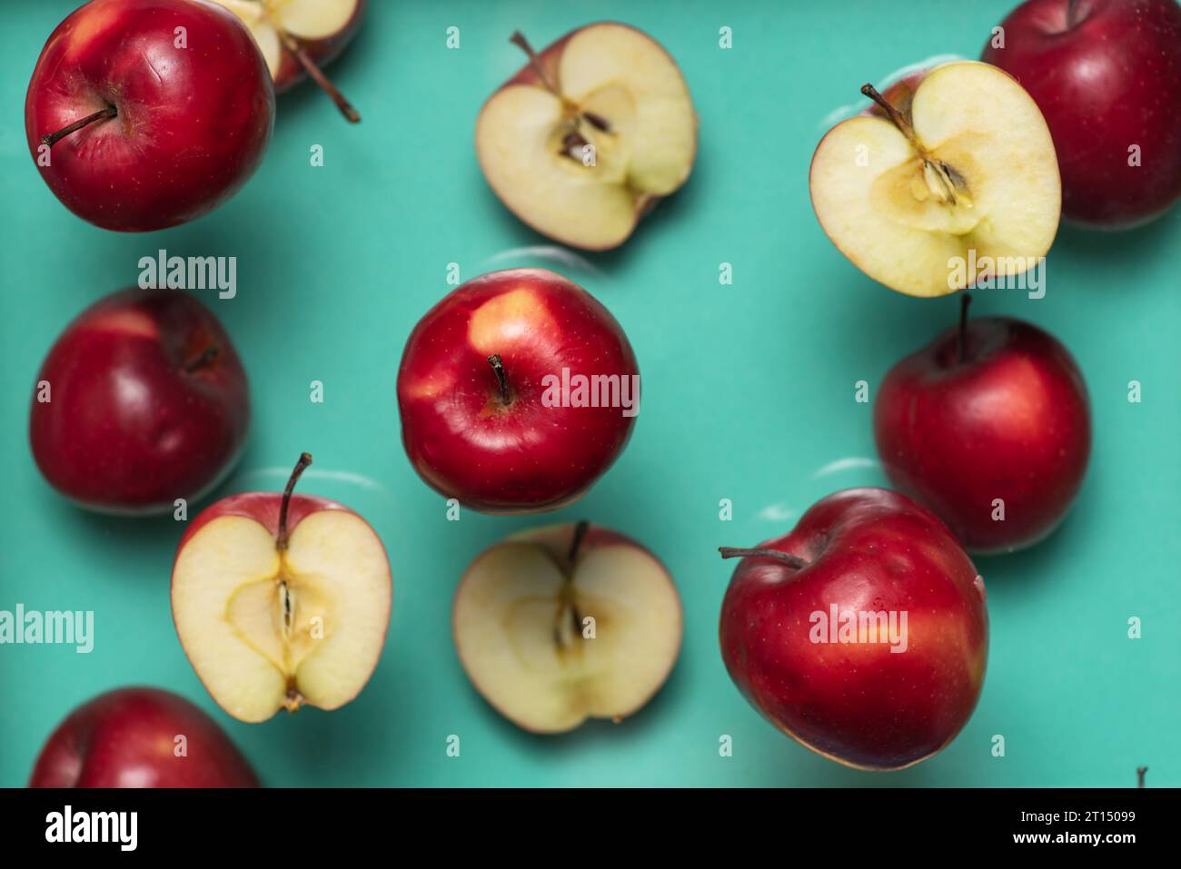 Whole and half red apples are floating on a light blue background Stock ...