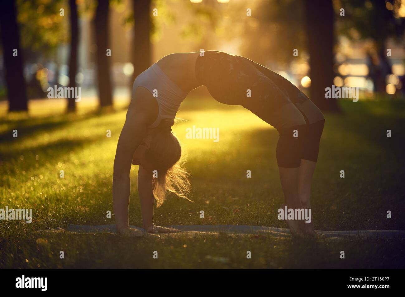 girl is doing yoga, standing in bridge wheel pose urdhva dhanurasana in ...