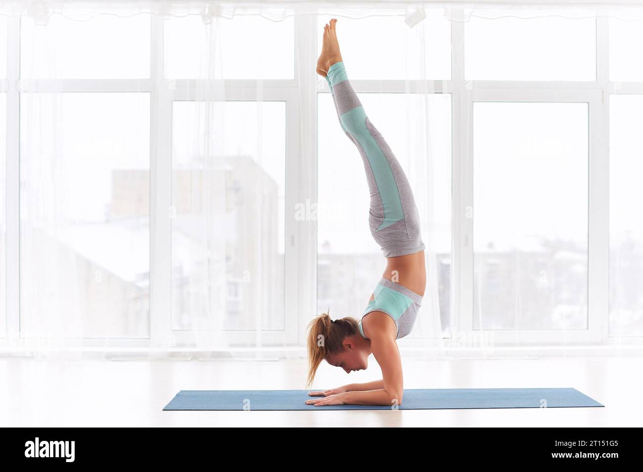 Young woman practicing yoga, standing in Pincha Mayurasana - Forearm ...