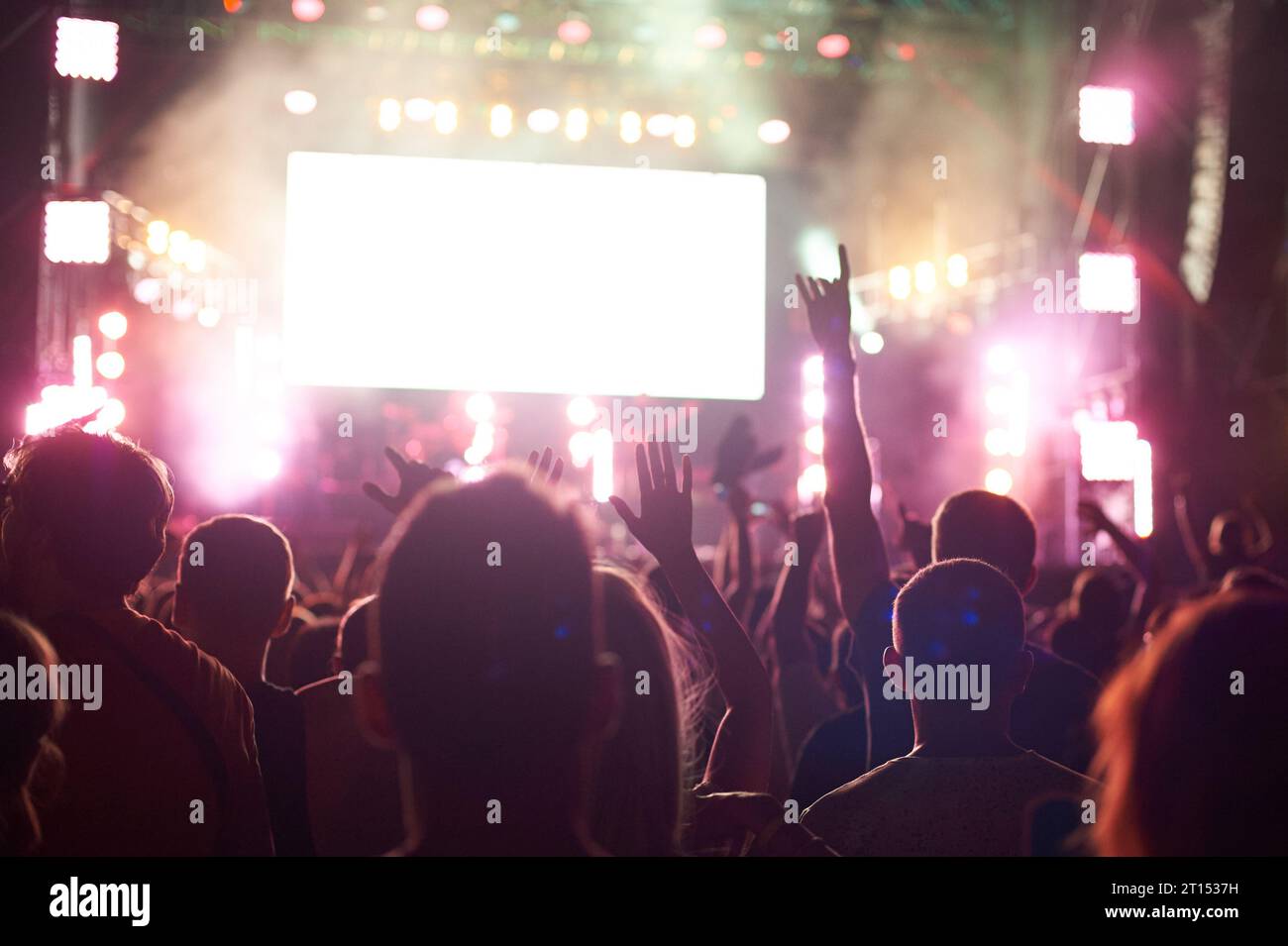 Crowd of audience with hands raised at a music festival. Lights ...