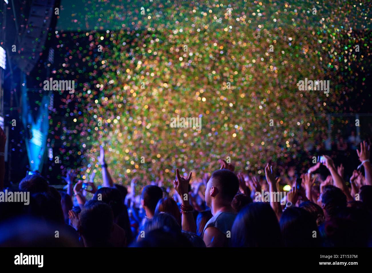Crowd of audience with hands raised at a music festival. Lights ...