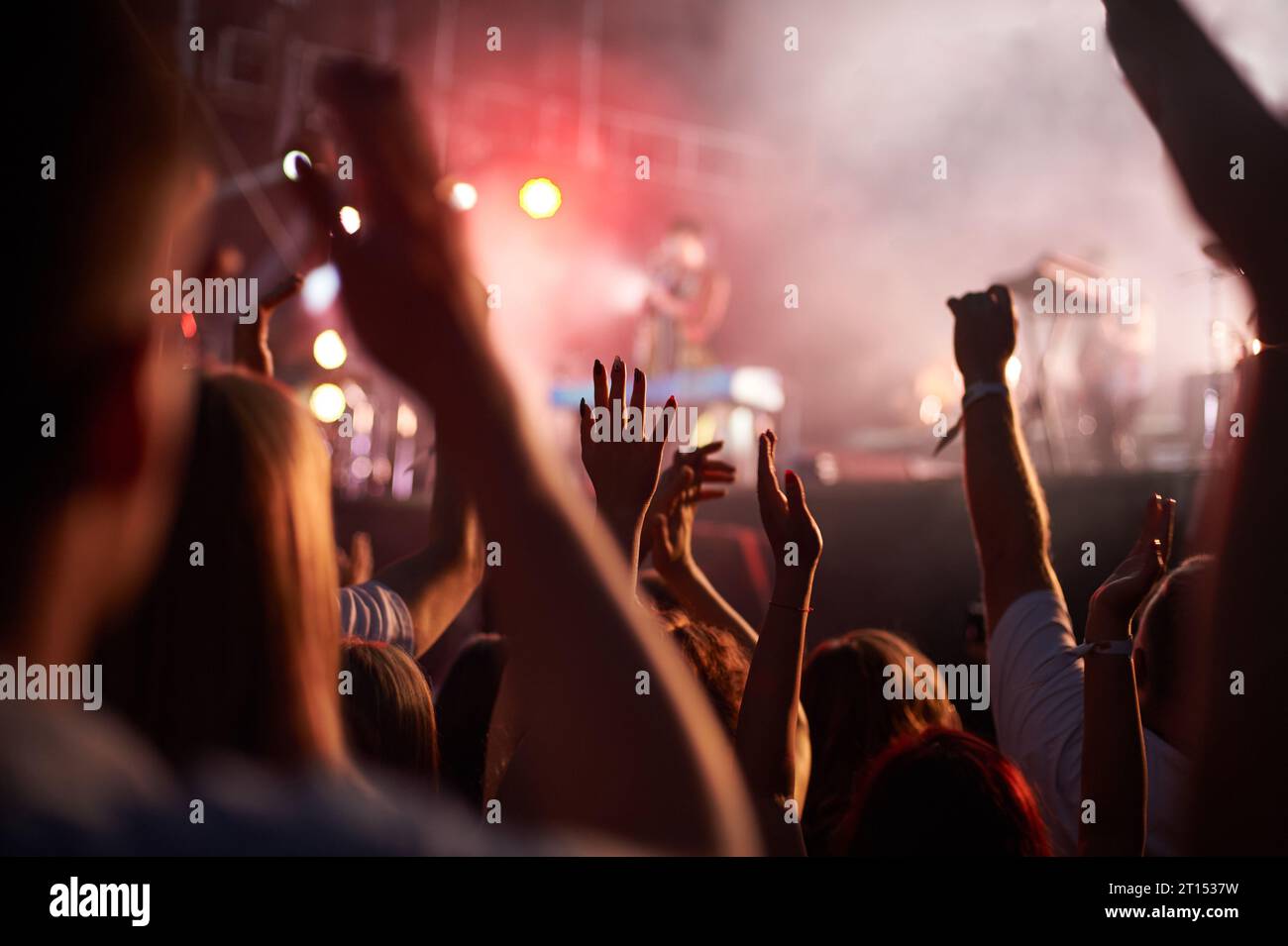 Crowd of audience with hands raised at a music festival. Lights ...