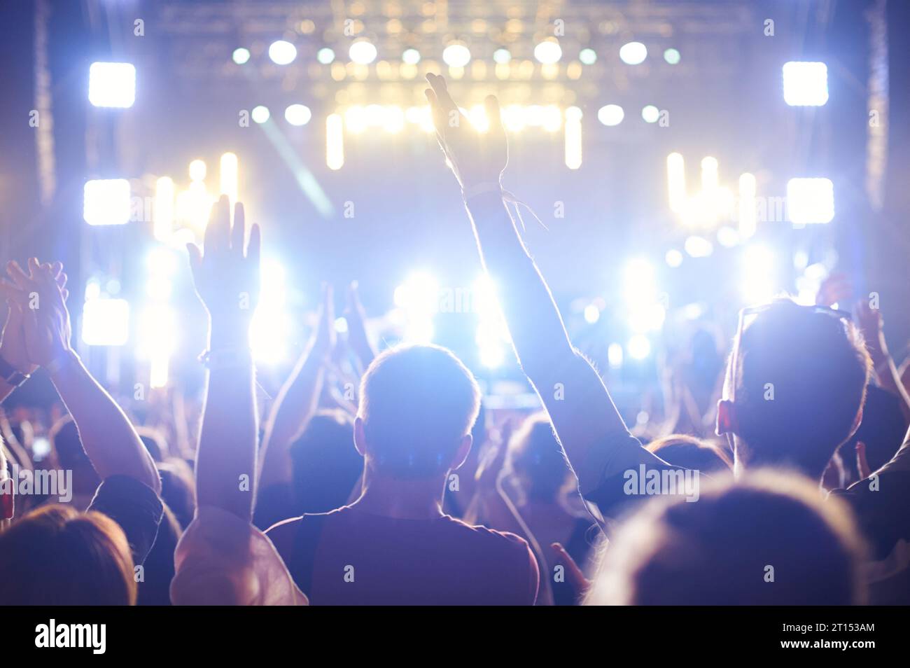 Crowd of audience with hands raised at a music festival. Lights ...