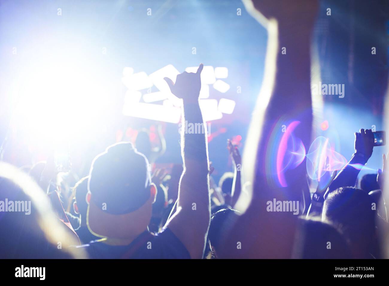 Crowd of audience with hands raised at a music festival. Lights ...