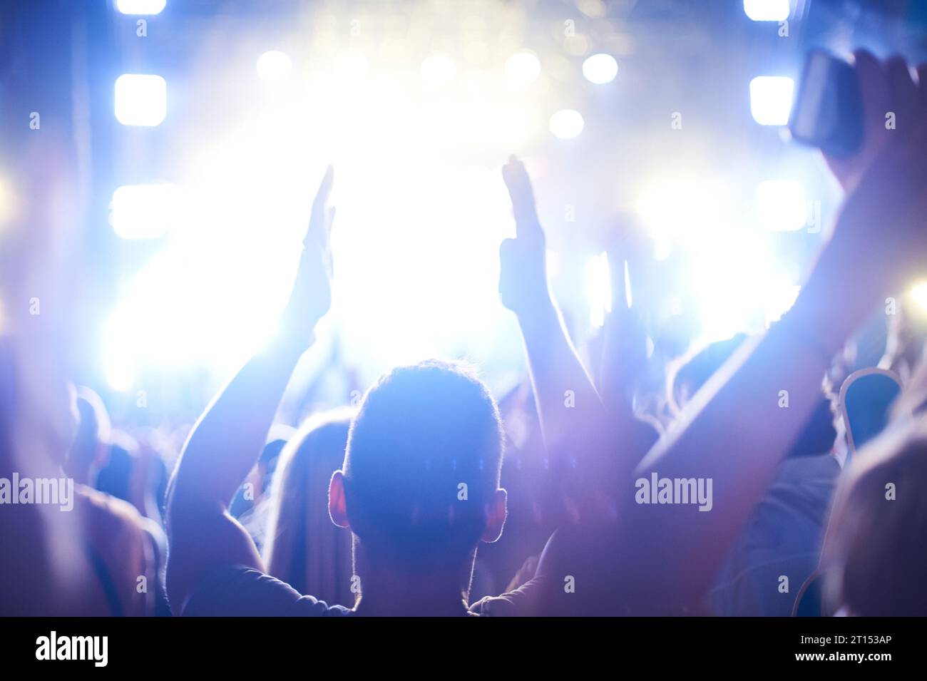 Crowd of audience with hands raised at a music festival. Lights ...