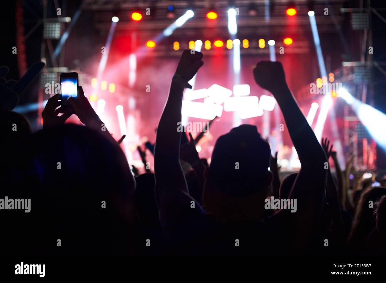 Crowd of audience with hands raised at a music festival. Lights ...