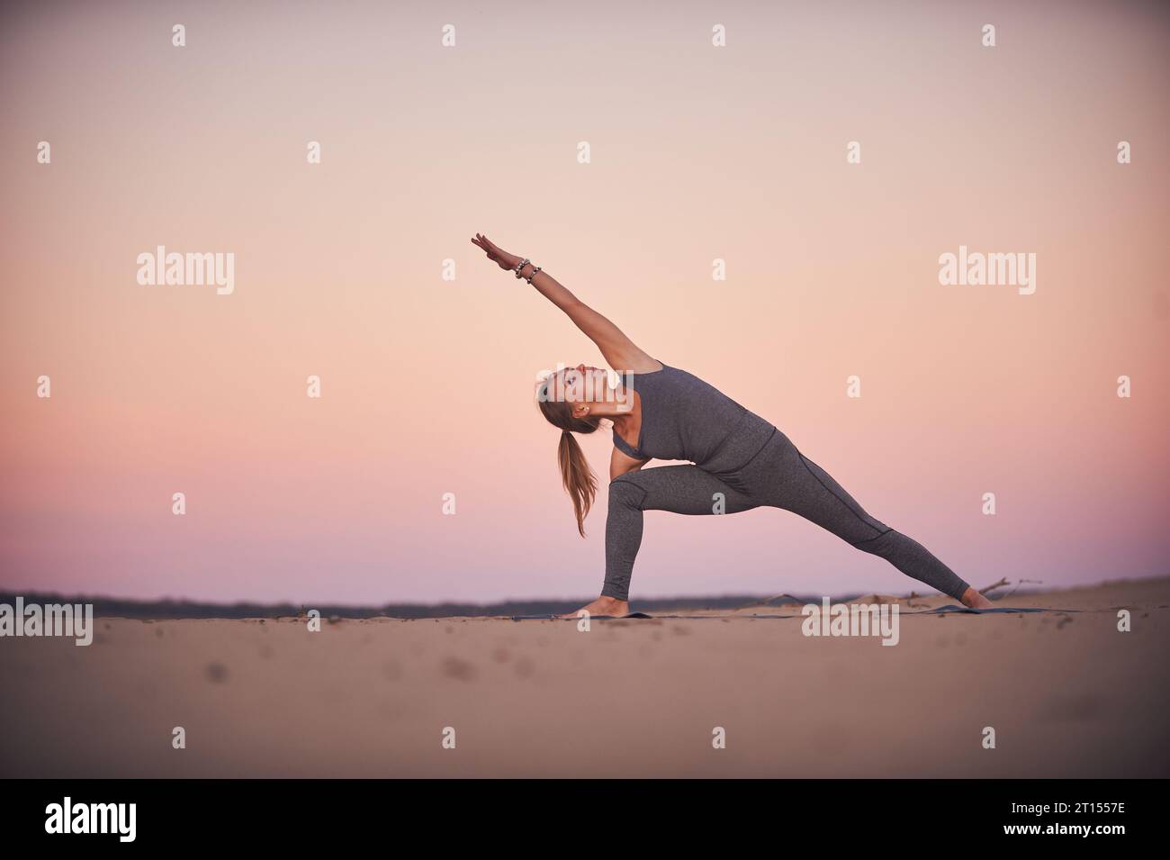 Beautiful young woman practices yoga asana Utthita Parshvakonasana ...