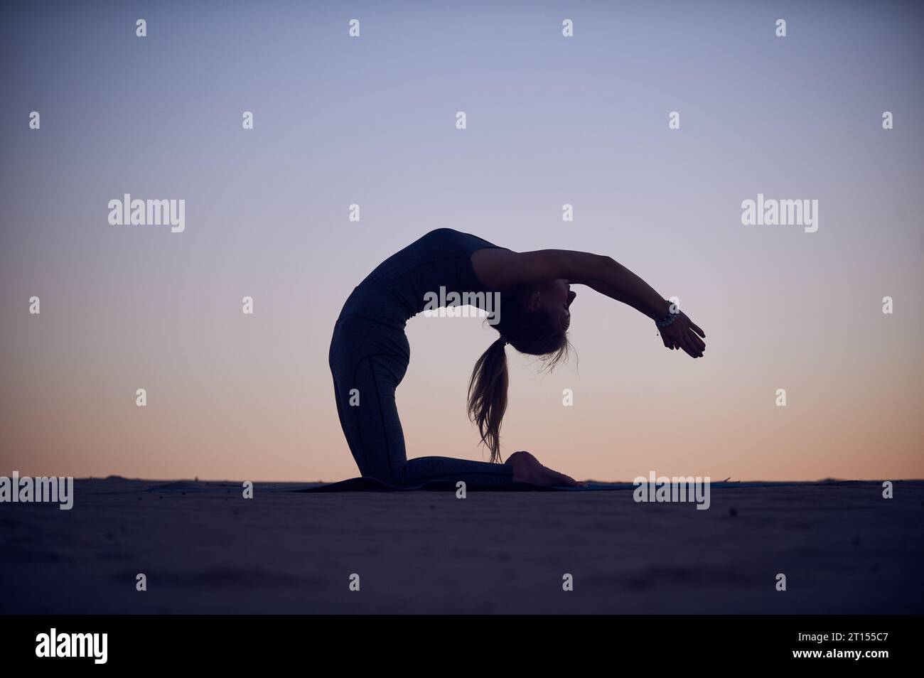 Beautiful young woman practices advanced variation of camel pose ...