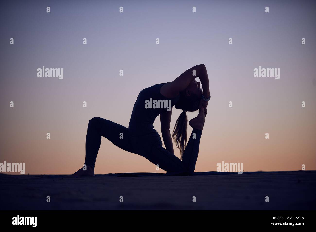 Beautiful young woman practices yoga asana King Pigeon pose ...