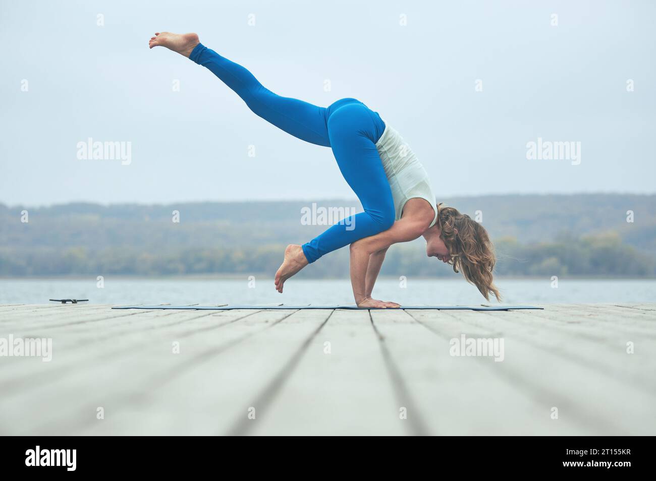 Beautiful young woman practices yoga asana Eka Pada Bakasana - one leg ...