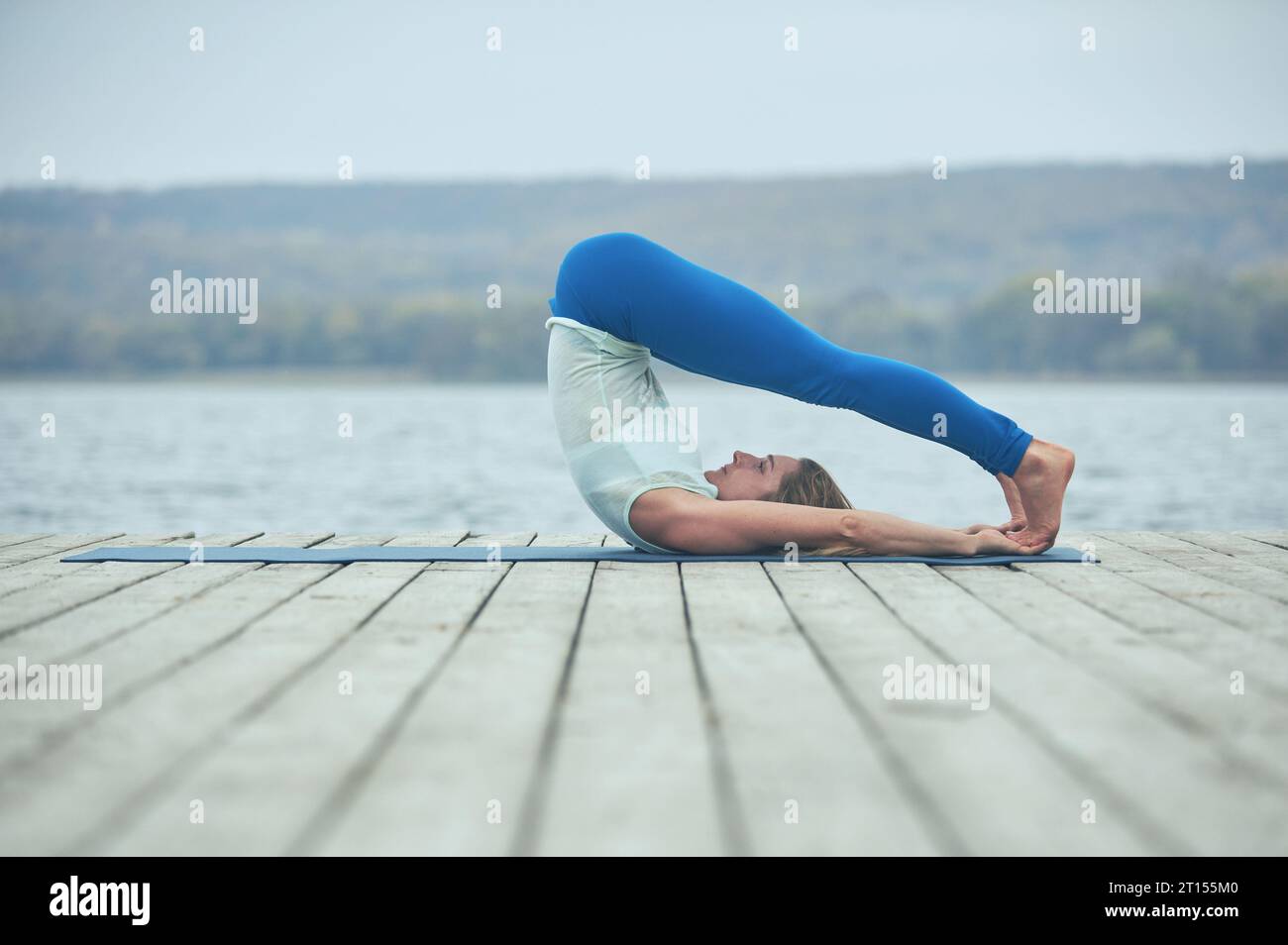 Beautiful young woman practices yoga asana Shirshasana - Headstand pose ...