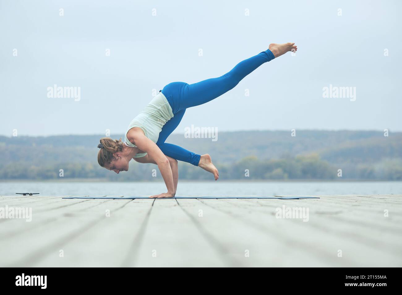 Beautiful young woman practices yoga asana Eka Pada Bakasana - one leg ...