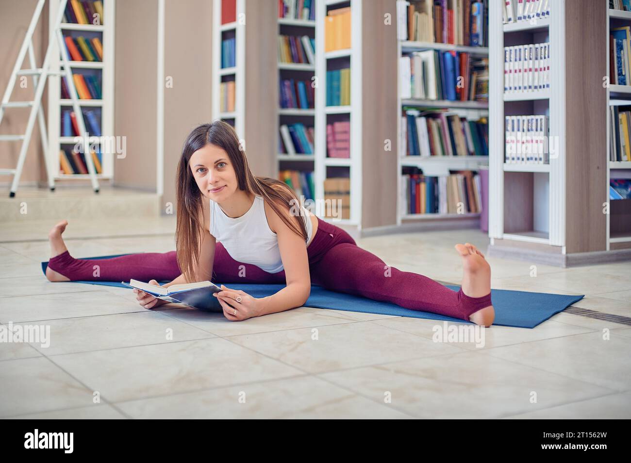 Beautiful young woman reading book and practices yoga asana ...