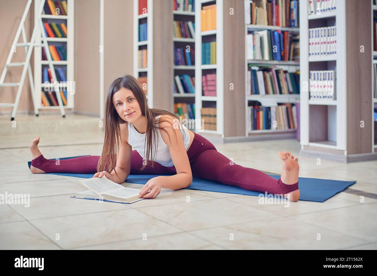 Beautiful young woman reading book and practices yoga asana ...