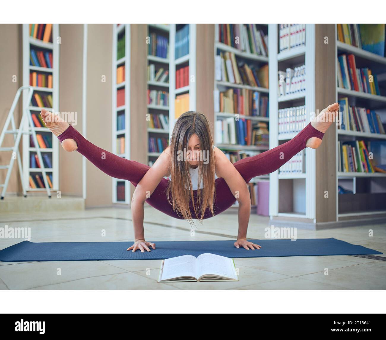 Beautiful woman reading book and practices handstand yoga asana ...