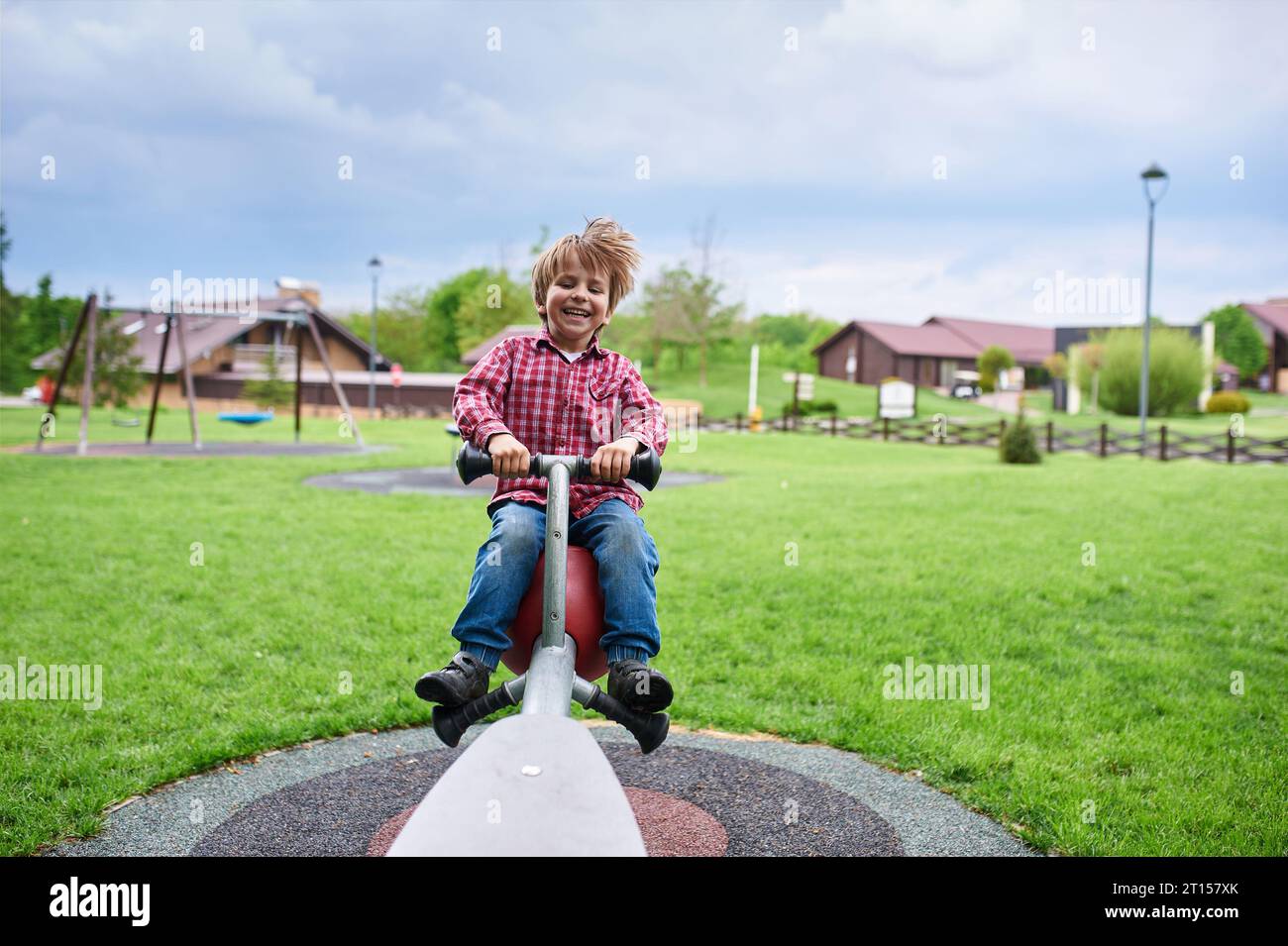 Outdoors portrait of cute preschool laughing boy swinging on a swing at ...