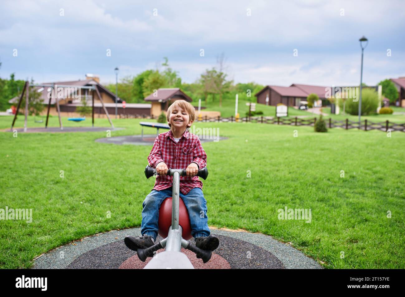 Outdoors portrait of cute preschool laughing boy swinging on a swing at ...