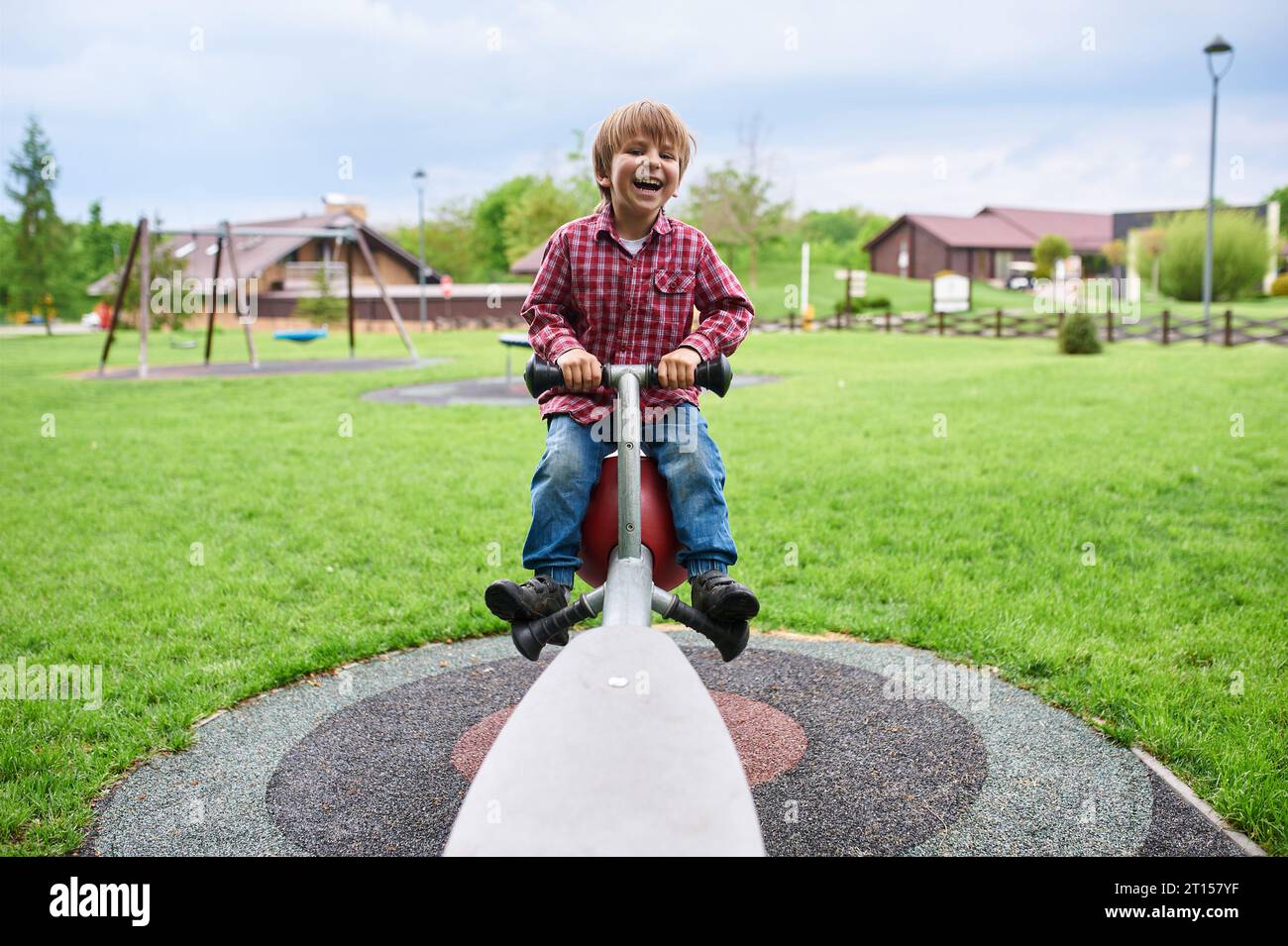 Outdoors portrait of cute preschool laughing boy swinging on a swing at ...