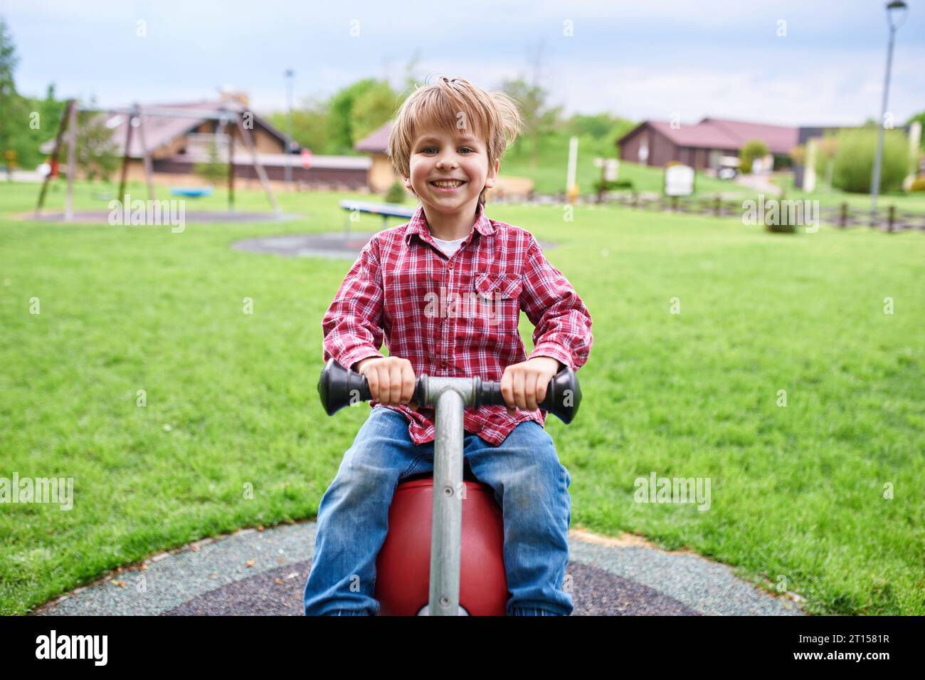 Outdoors portrait of cute preschool laughing boy swinging on a swing at ...