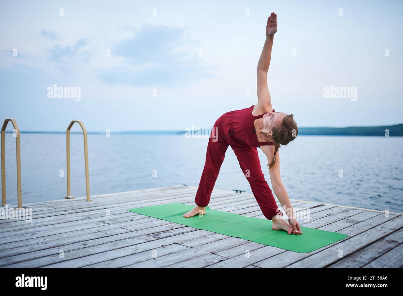 Beautiful young woman practices yoga asana Triangle Pose Trikonasana on ...