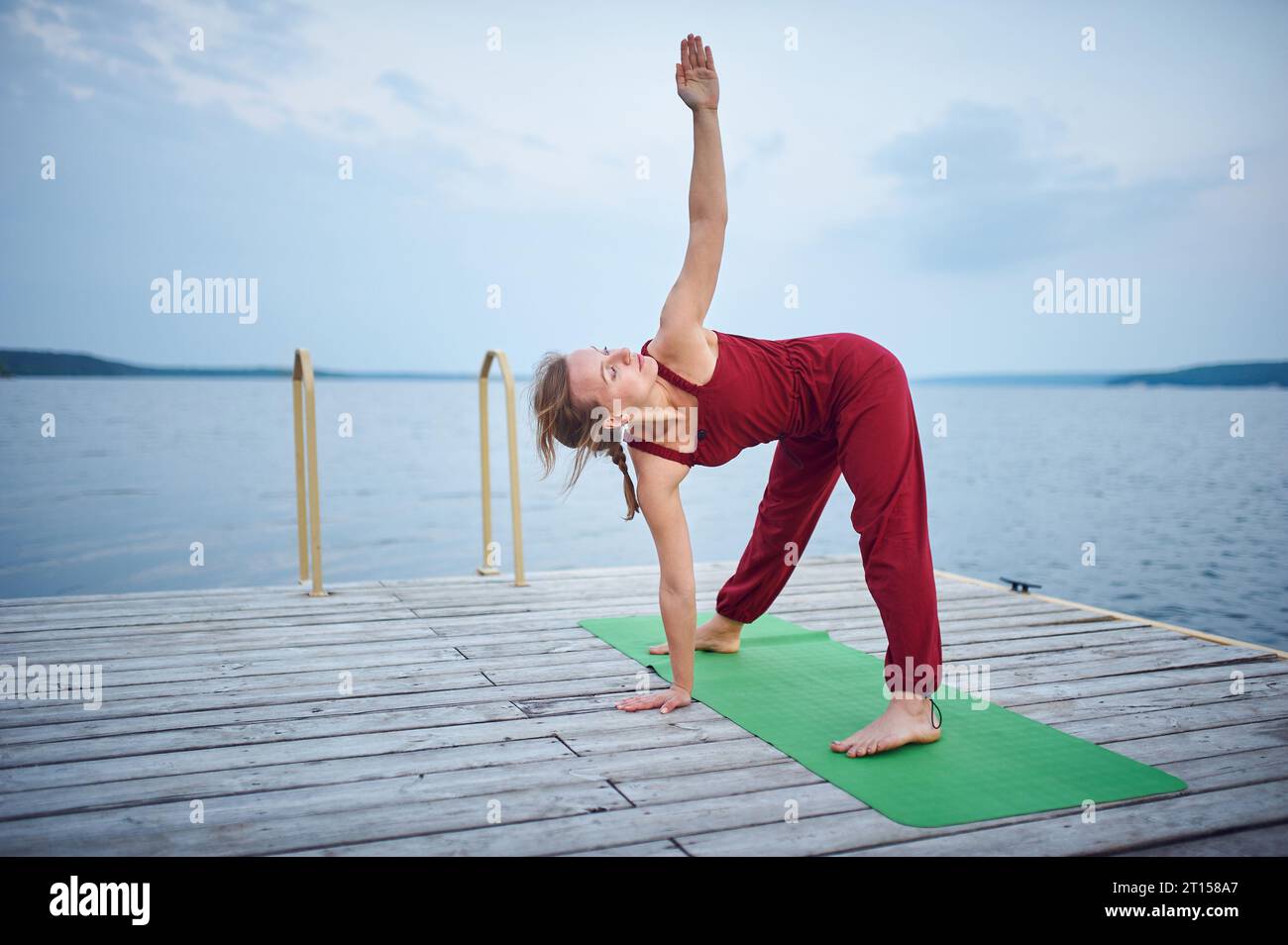 Beautiful young woman practices yoga asana Triangle Pose Trikonasana on ...