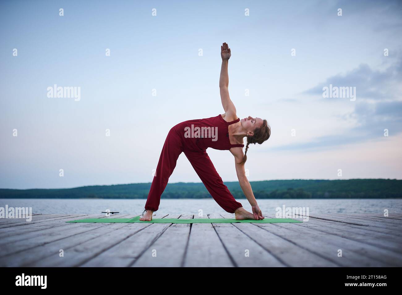 Beautiful young woman practices yoga asana Triangle Pose Trikonasana on ...