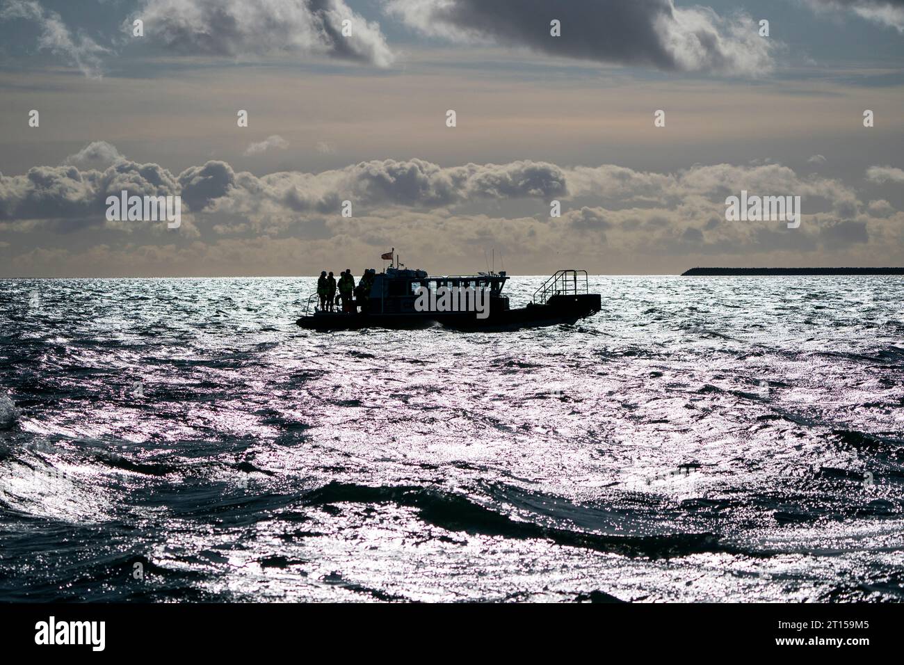 Personnel on a support boat observing a heavy duty ocean boom being ...