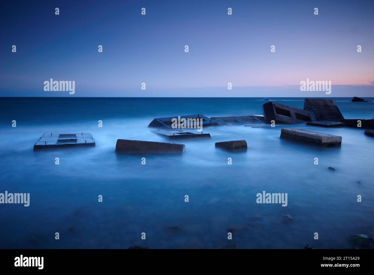 Massive concrete blocks form a breakwater with soft blur sea at night ...