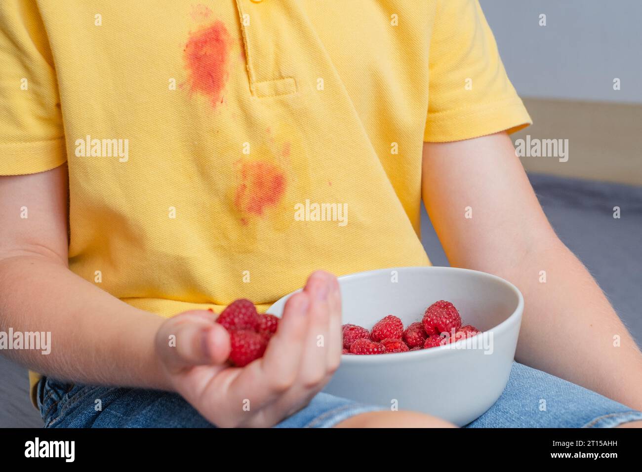 Unrecognizable child eating raspberry with hands. Dirty berry stains on ...