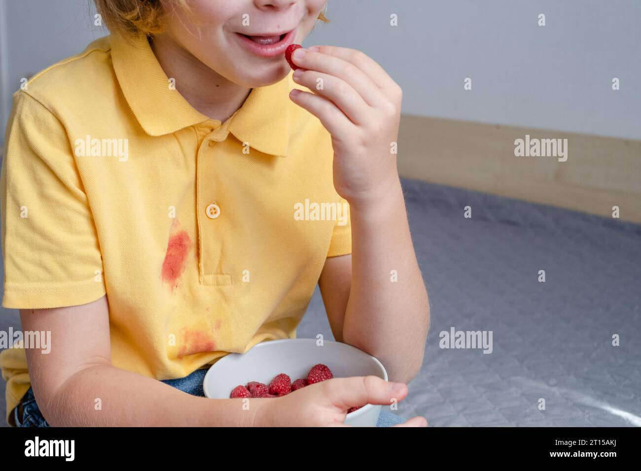 Unrecognizable child eating raspberry with hands. Dirty berry stains on ...