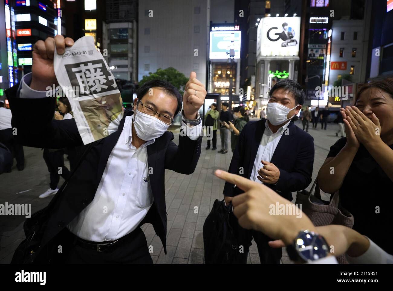 Passers-by pick up an extra edition of the Yomiuri Shimbun reporting ...