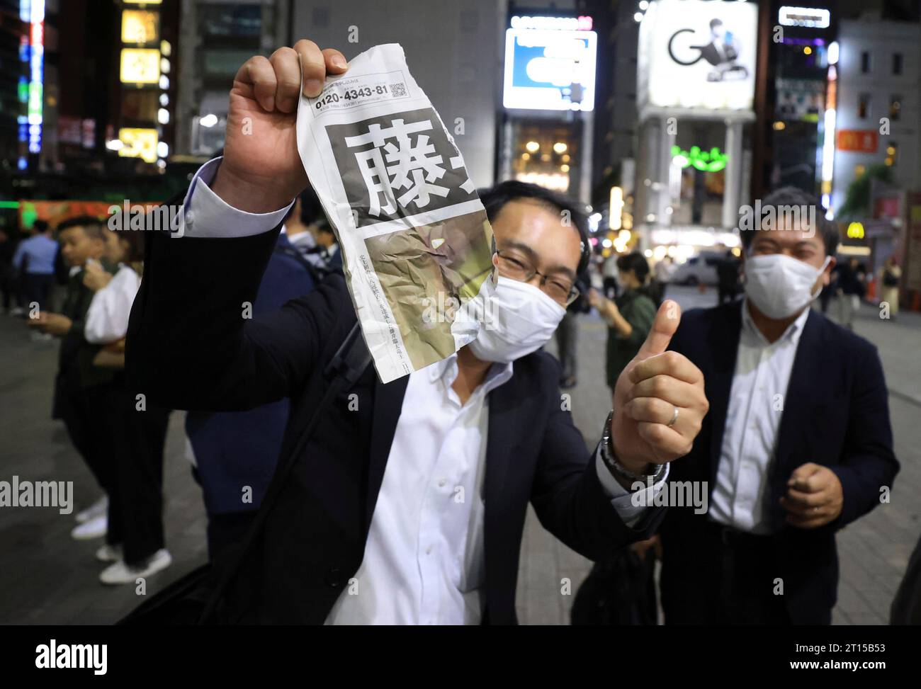 Passers-by pick up an extra edition of the Yomiuri Shimbun reporting ...