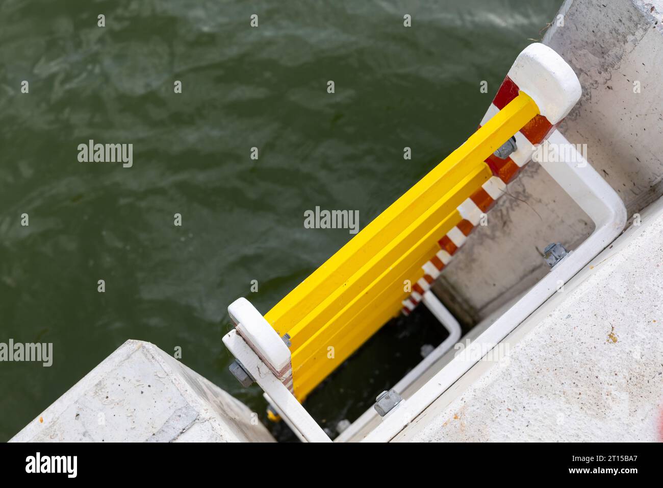 Steel yellow ladder into the water on the concrete quay. Safety of the ...
